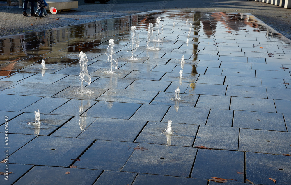 square granite paving stacked in a strip in sidewalk,boy, water sprays ...