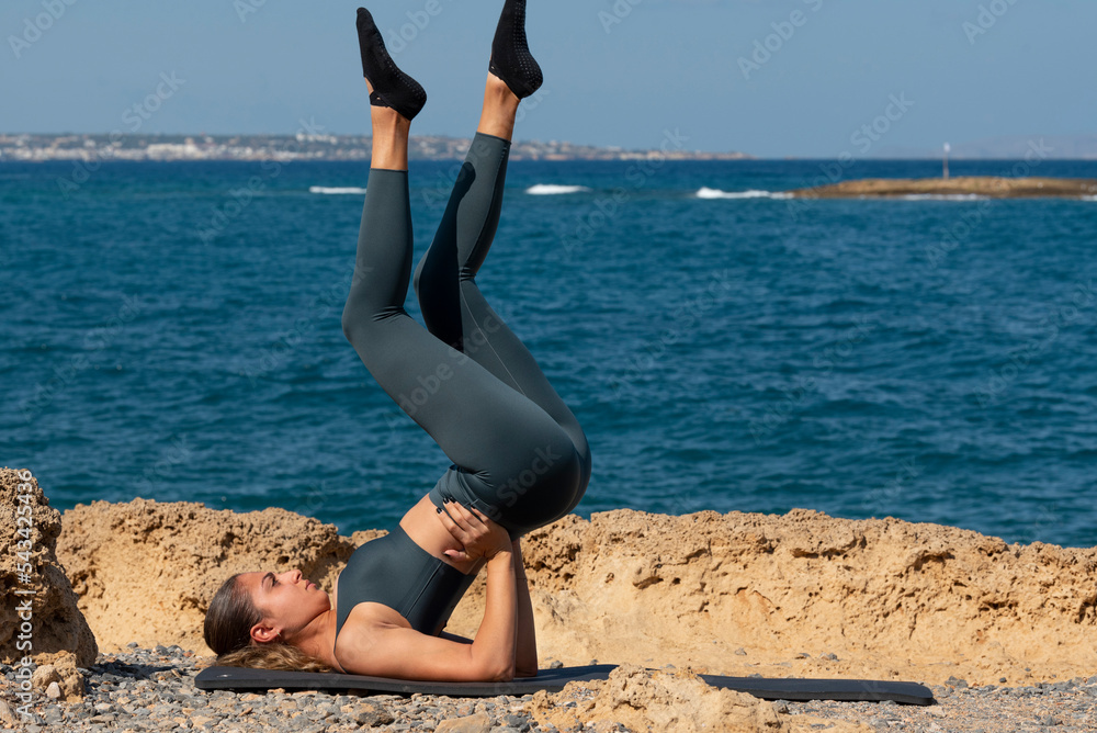 Malia, Crete, Greece. 2022. Pilates exercises on the beach . Shoulder ...
