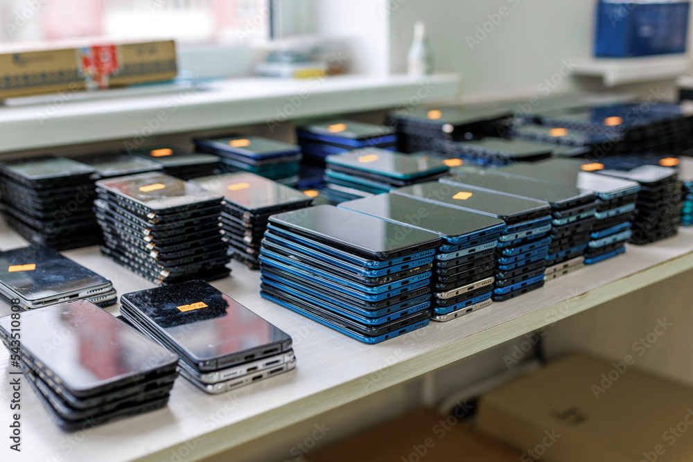 Used phones stacked on top of each other. Background of damaged mobile ...