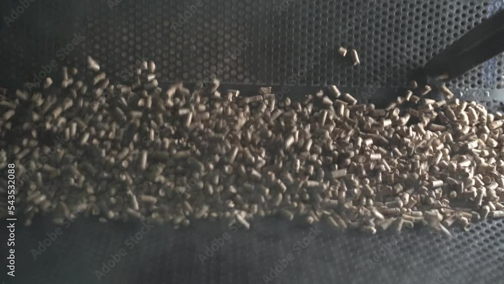 Cut small brown wooden pellets rotate in machine drum during production ...