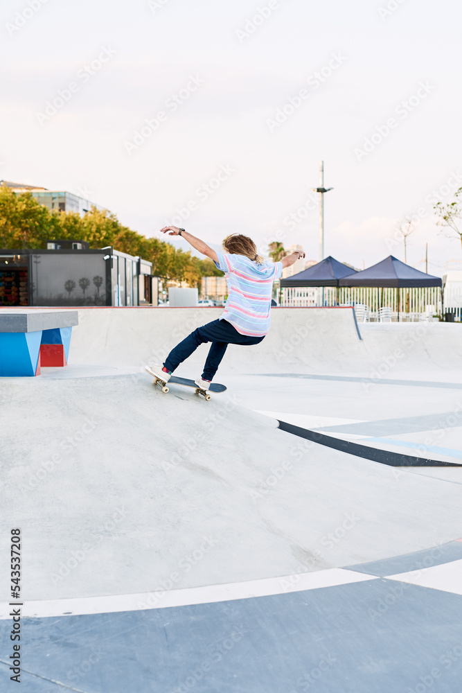 Back view of skater performing trick on hill in skate park. Stock Photo ...