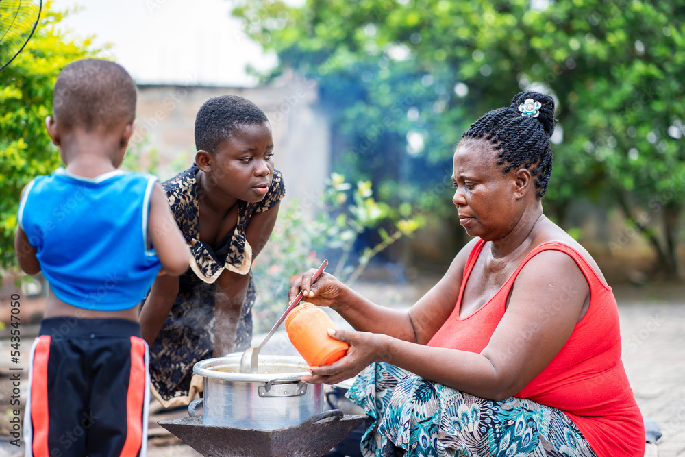 image of african woman and two kids in local kitchen outside- cooking ...