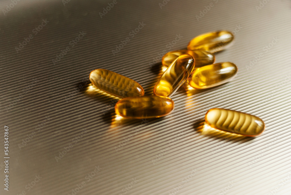 Omega-3 in gelatin capsules on a gray striped background. Vitamins for ...