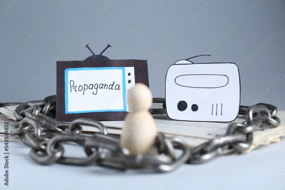 Propaganda concept. Human mired in media field. Chained wooden figure ...