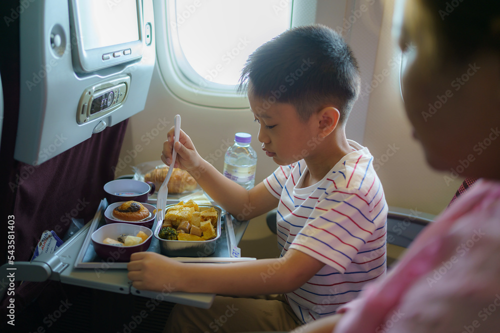 Asian Child in airplane window seat. Kids flight meal. Children fly ...
