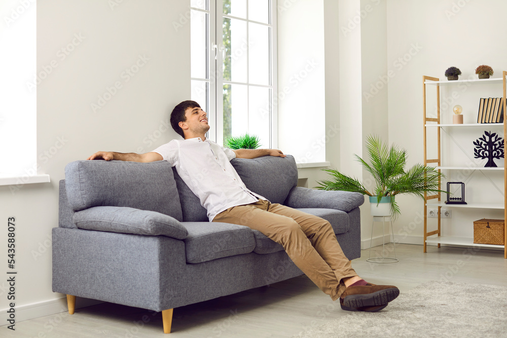 Satisfied calm young man resting after hard day's work sitting on ...