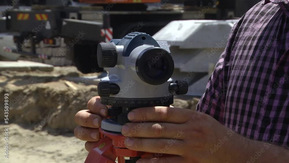 Surveyor worker with theodolite equipment at construction site. Optical ...