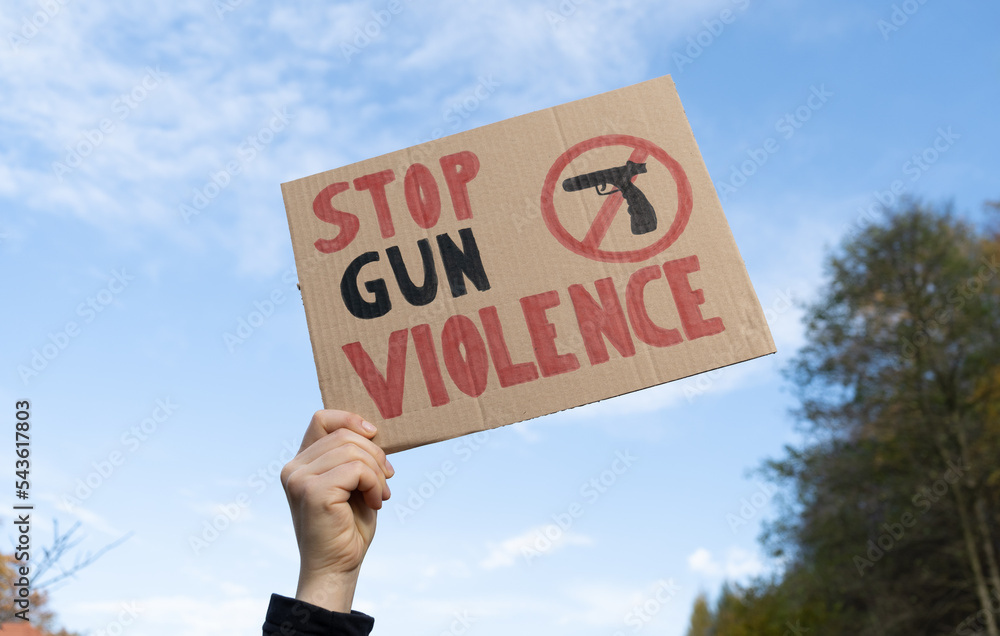 Hand holding a sign with slogan Stop Gun Violence and black pistol ...