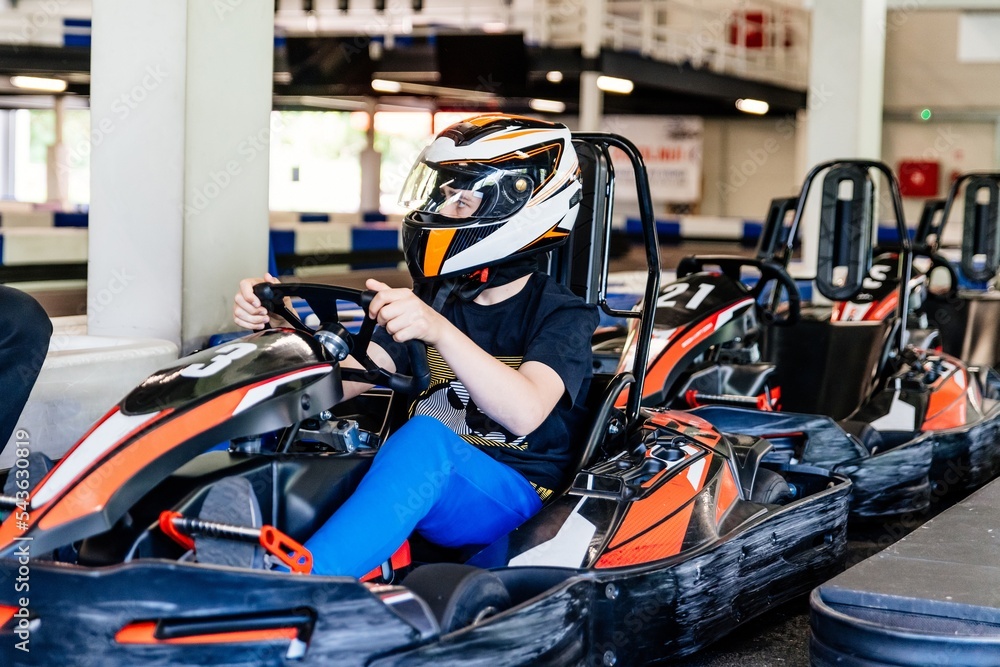 teenage boy in a racing helmet gets ready to race. Indoor kart track ...