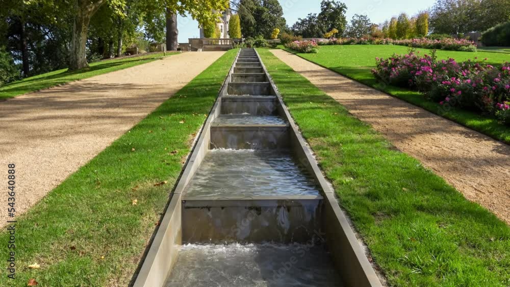 stepped water feature in designer garden with topiary hedges and flower ...
