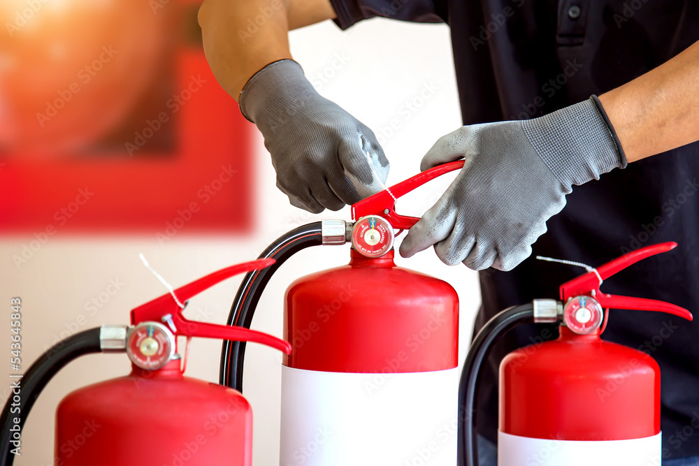 Close up fire extinguisher and firefighter checking pressure gauge ...