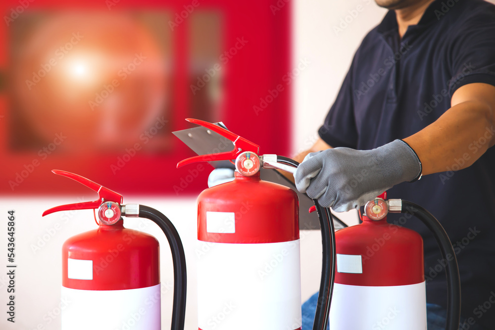 Close up fire extinguisher and firefighter checking pressure gauge ...