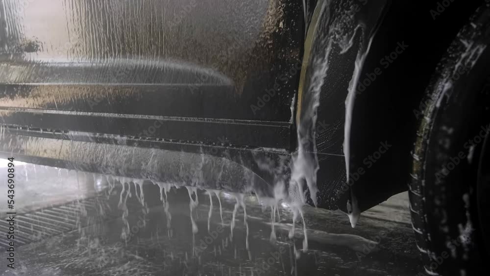 Water drips and drips down the car. Black modern car at a car wash ...