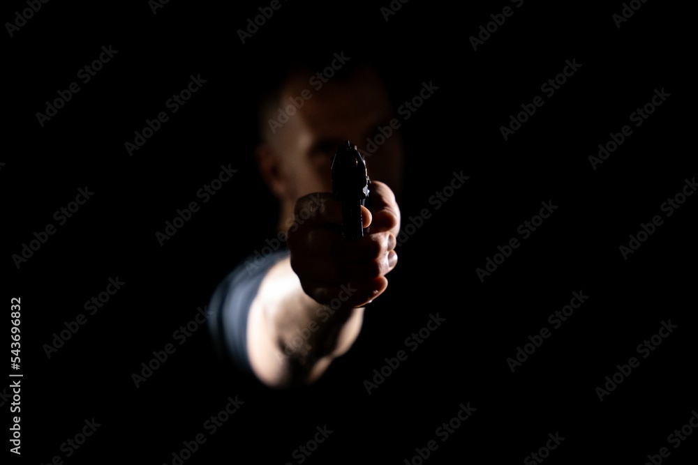 Man in a dark shallow focus pointing a gun to the camera foto de Stock ...