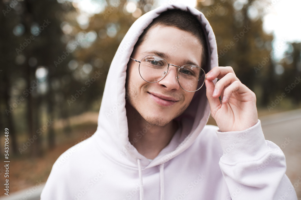 Smiling cute teenager boy 19-20 year old wear glasses and hood over ...