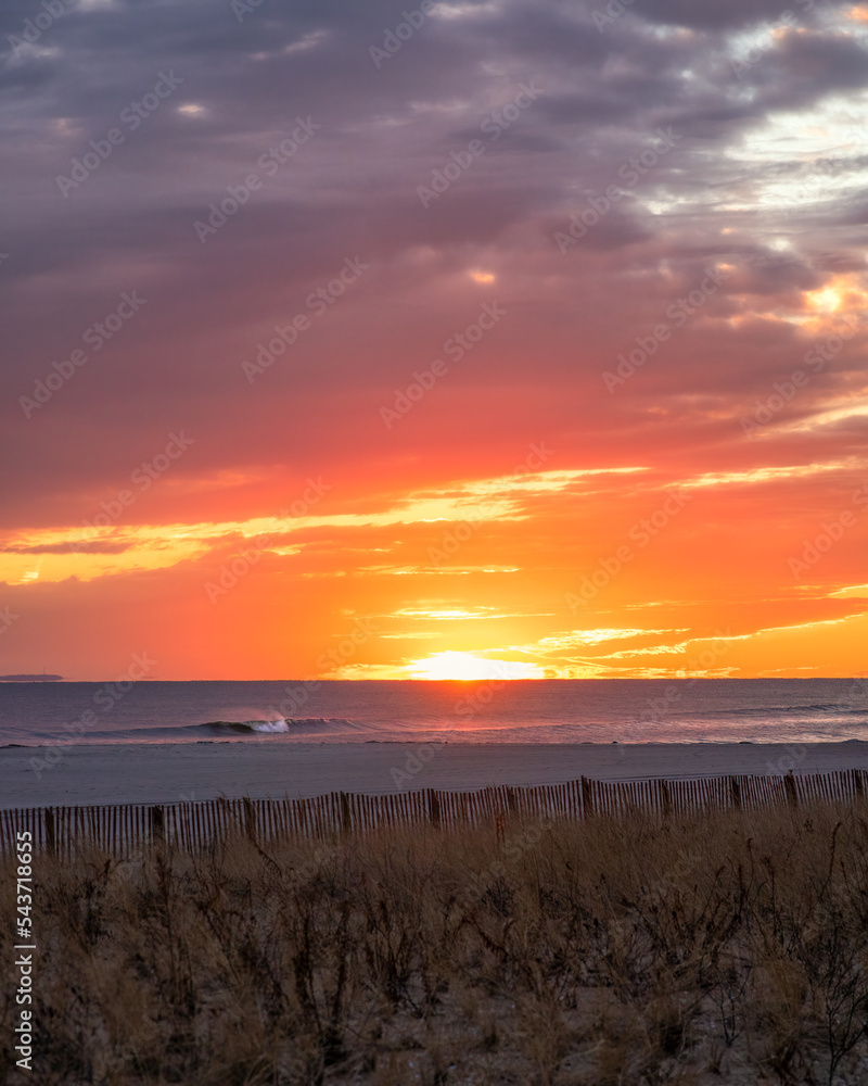 Calm beach scene under a vibrant sunset as the sun dips below the ...