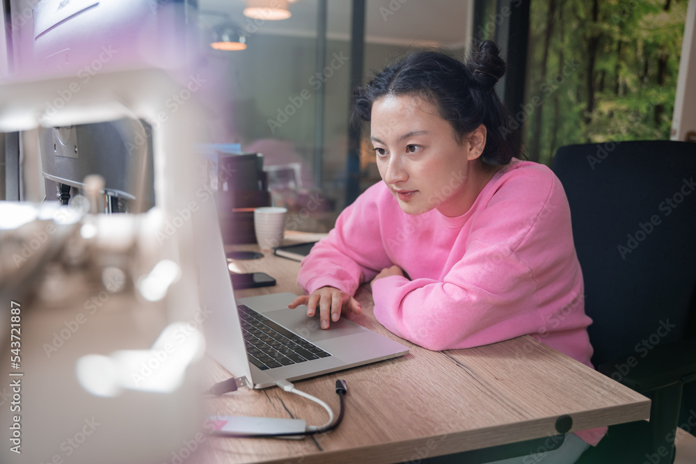 Calm university student watching attentively at the laptop computer ...