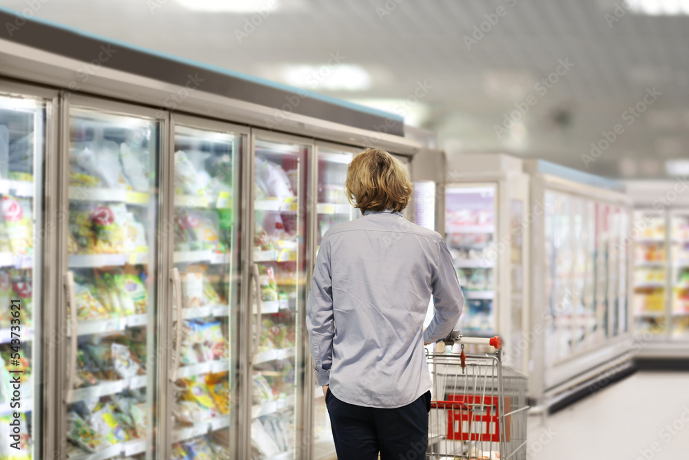 Man choosing frozen food from a supermarket freezer., reading product ...