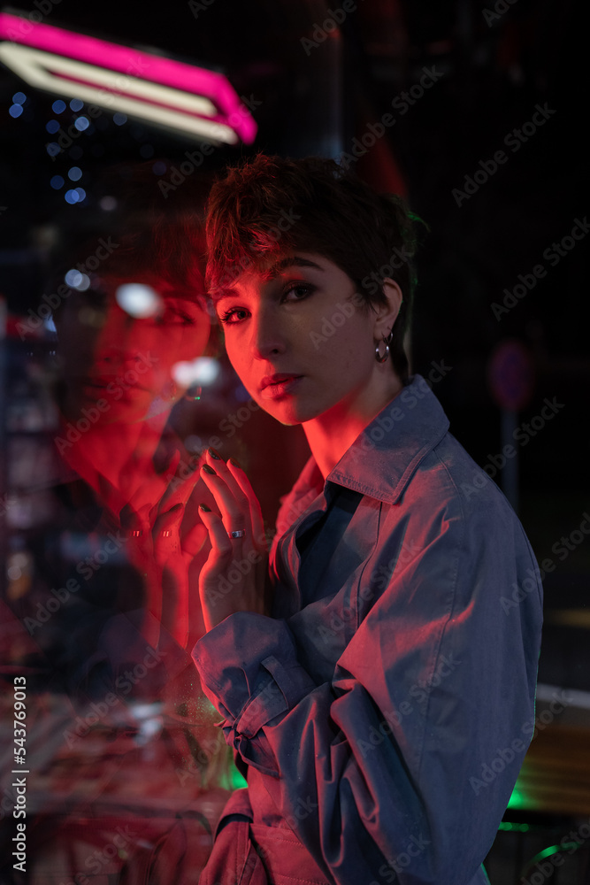 Sad lonely millennial woman with short hair in red neon light looking ...