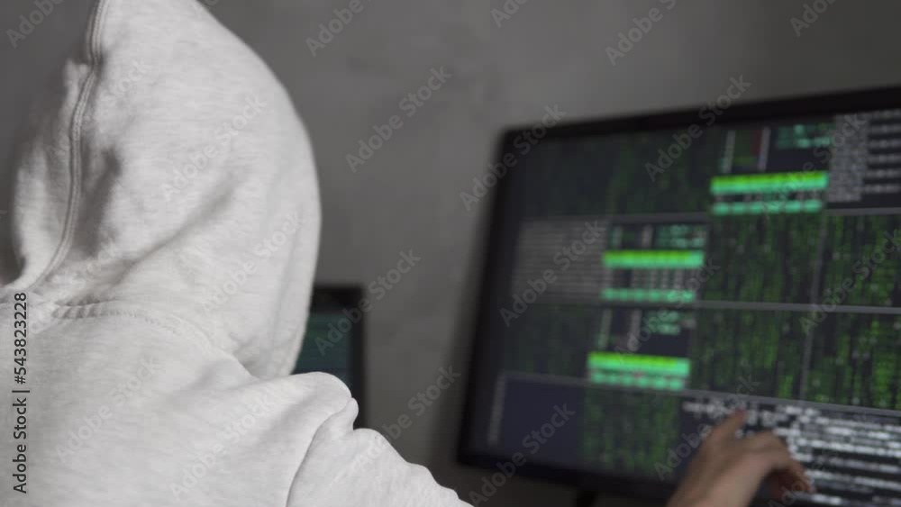 Hooded IT programmer working on desktop computer in data center ...