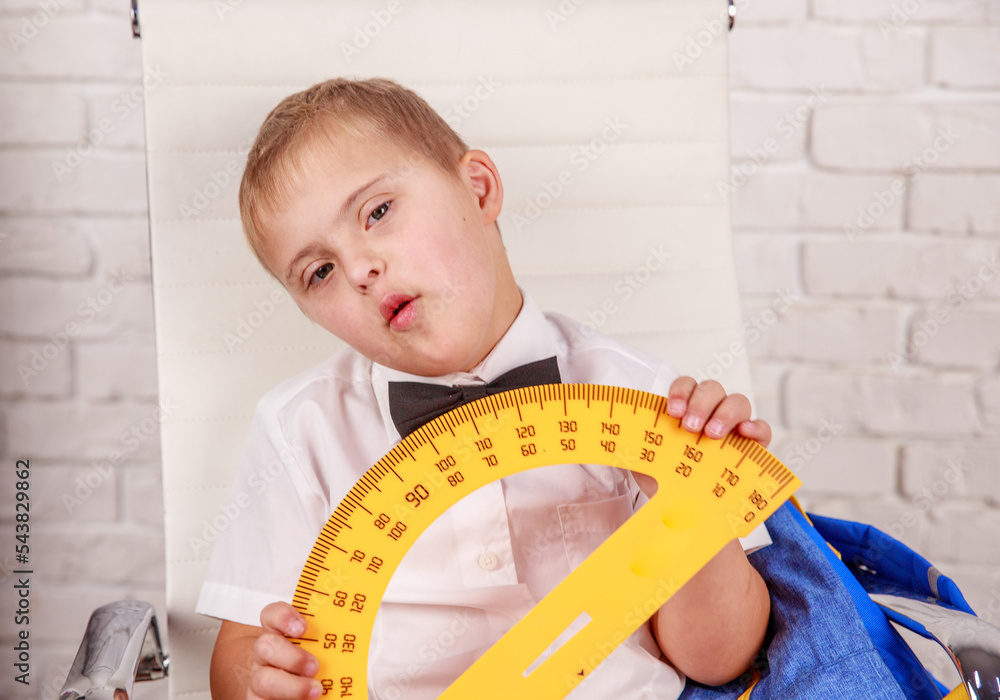 Happy boy with down syndrome holds a protractor ruler in his hands ...