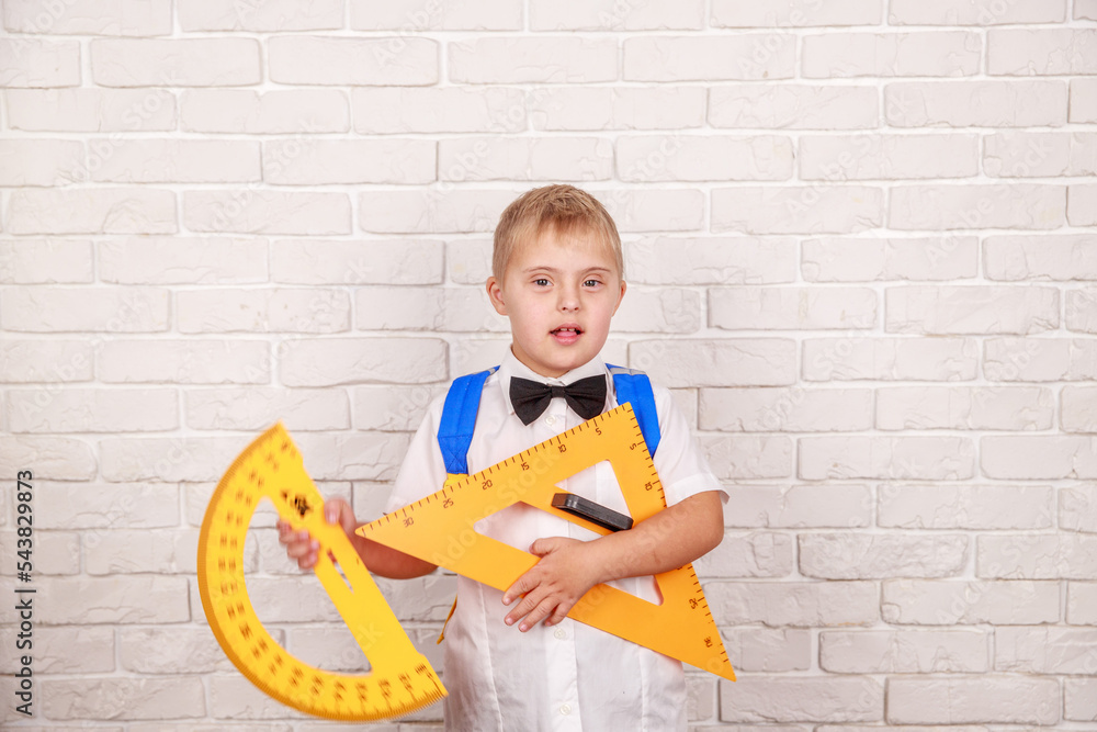 Happy boy with down syndrome holds a protractor and a triangle ruler in ...