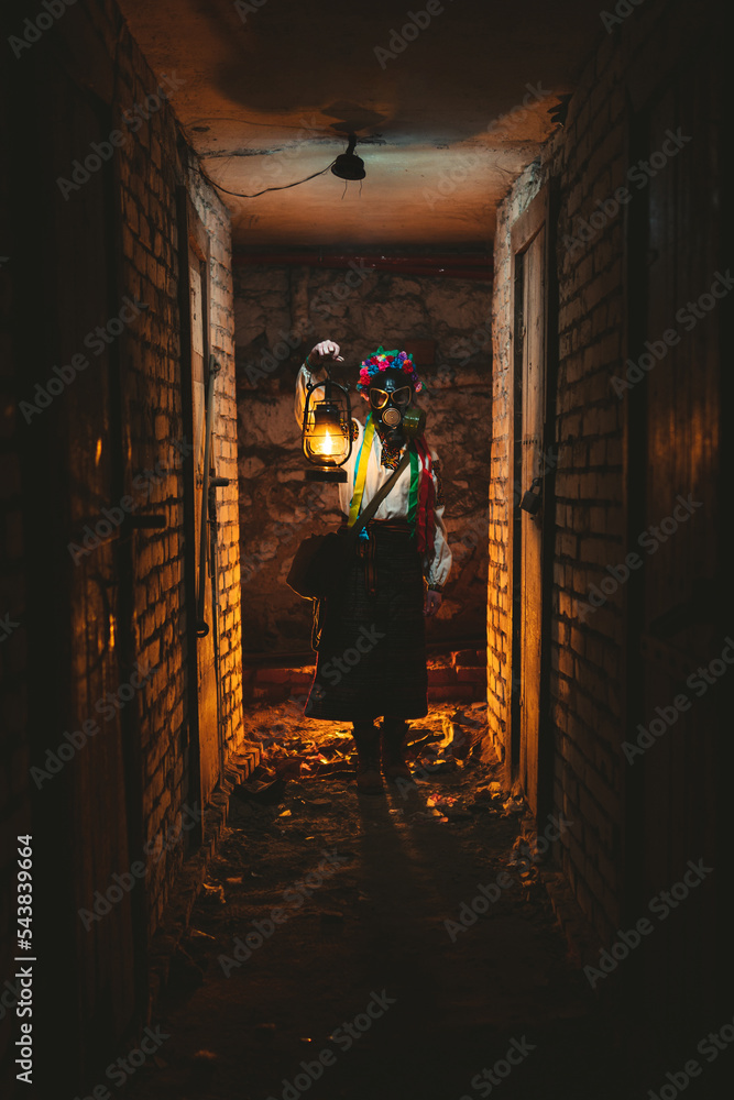 Ukrainian woman in a gas mask lights the way with an old gas lamp ...