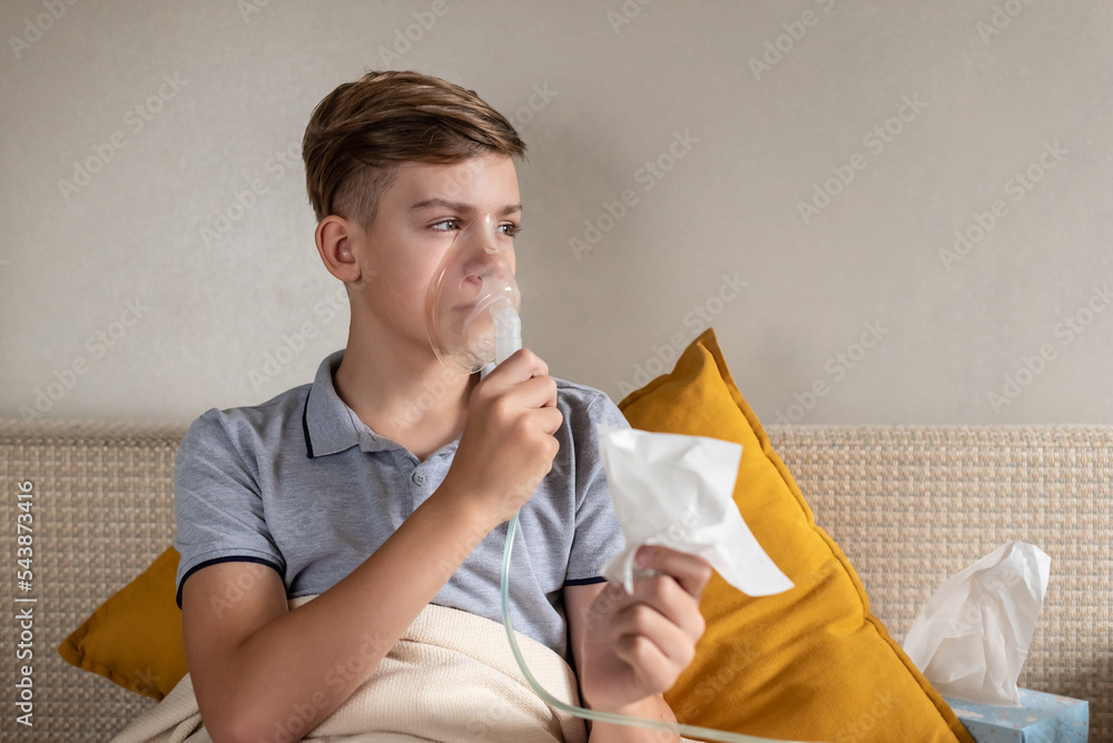 Sick teen boy with an inhaler. Unhealthy child doing inhalation at home ...