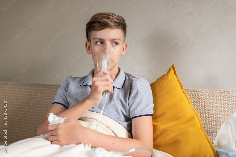 Sick teen boy with an inhaler. Unhealthy child doing inhalation at home ...