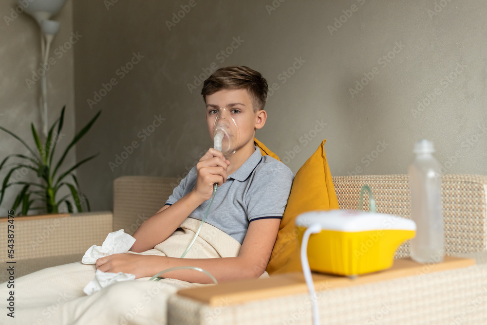 Sick teen boy with an inhaler. Unhealthy child doing inhalation at home ...