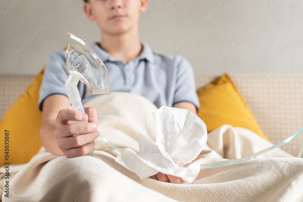 Sick teen boy with an inhaler. Unhealthy child doing inhalation at home ...