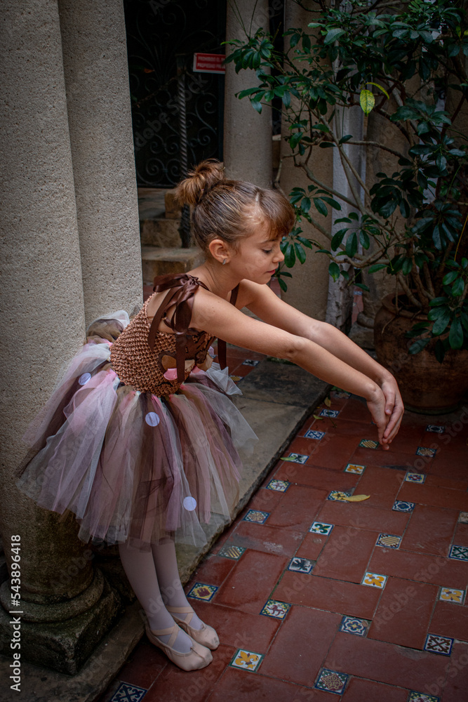 Niña pequeña posando baile ballet frente a una fachada o pared blanca ...