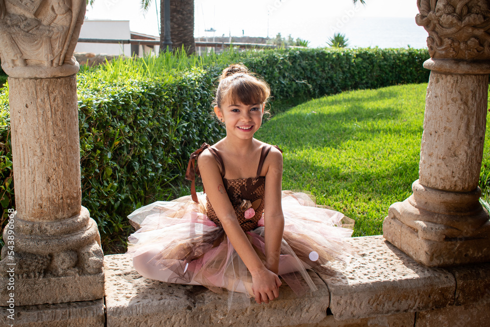 Niña pequeña bailando ballet en un jardín con muros románicos de piedra ...