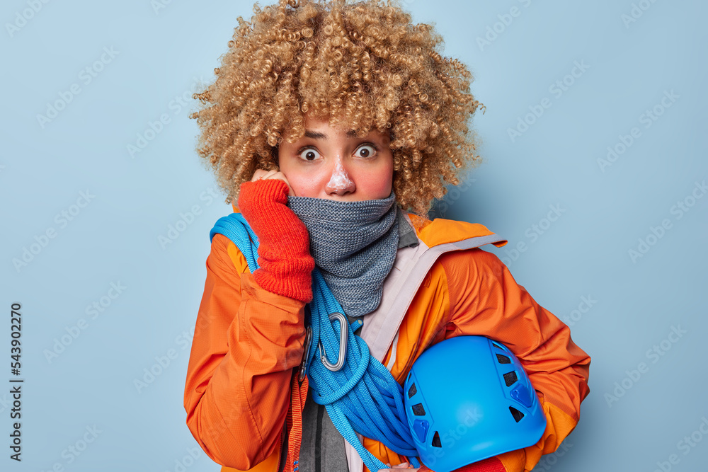 Amazed scared female alpinist feels cold while climbing mountain wears ...