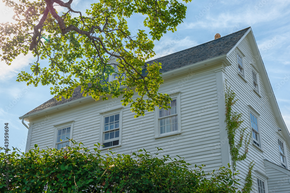 A historical two story white wooden house with multiple small glass ...