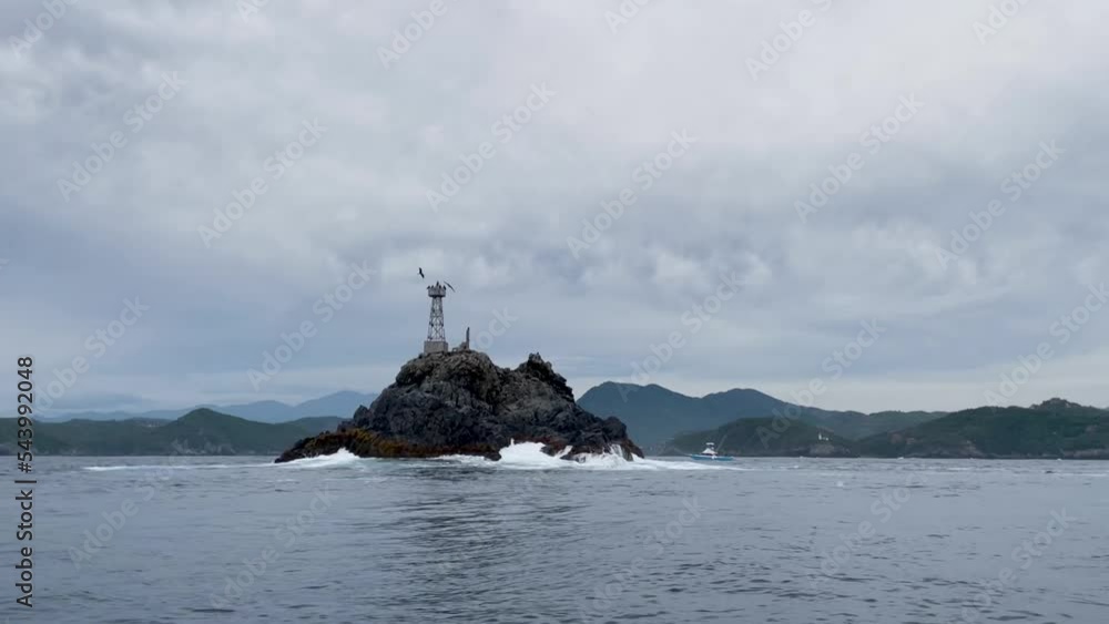 Birds flying around a lighthouse on top a little island in the middle ...