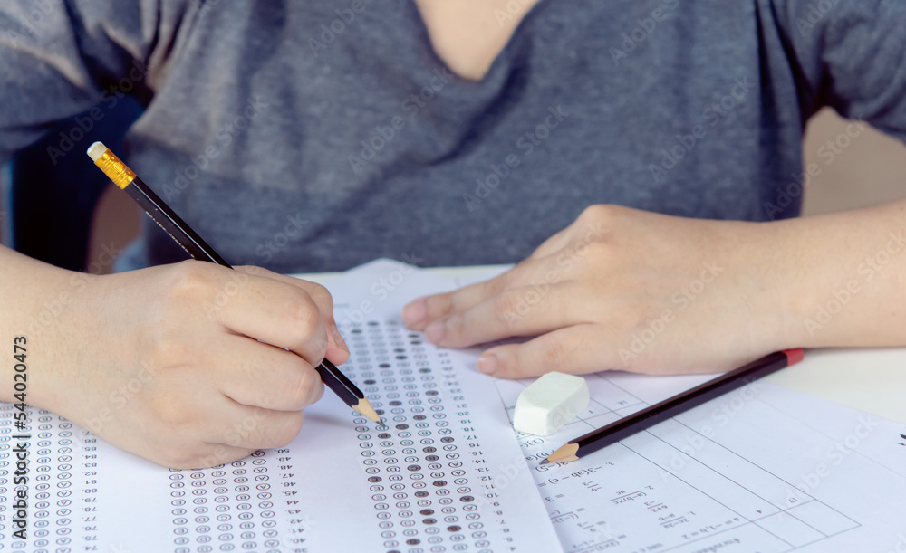 Students hand holding pencil writing selected choice on answer sheets ...