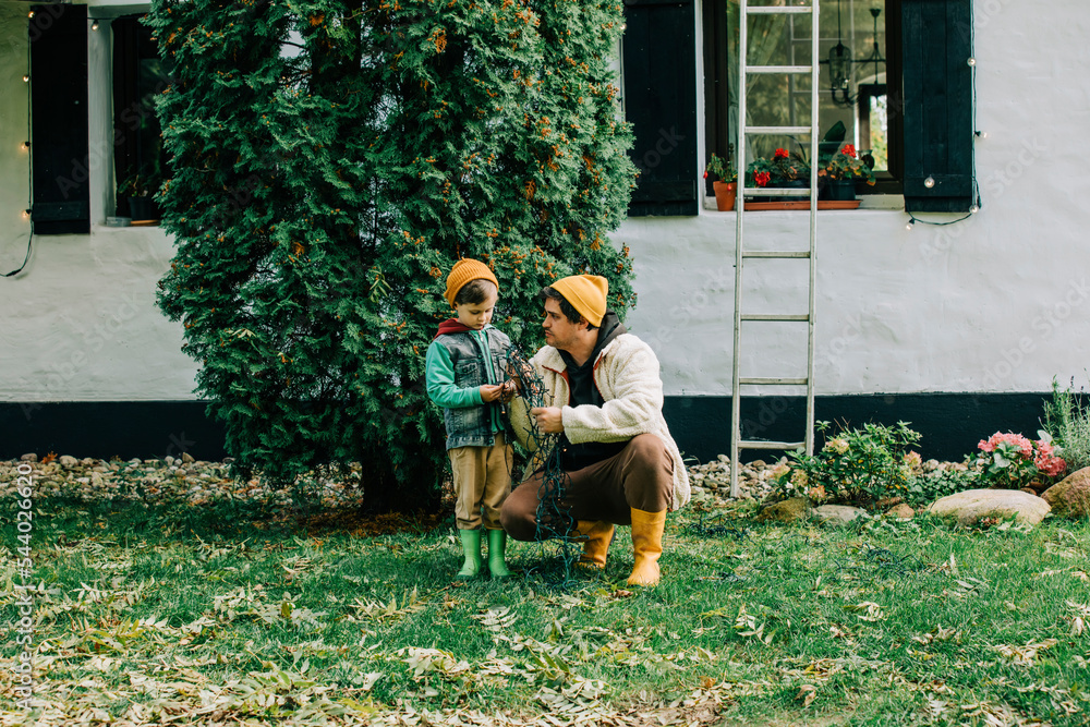 Father crouching by son in front of tree outside house Stock Photo ...