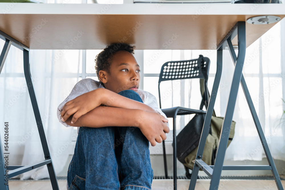 Boy hiding under table at home Stock Photo | Adobe Stock