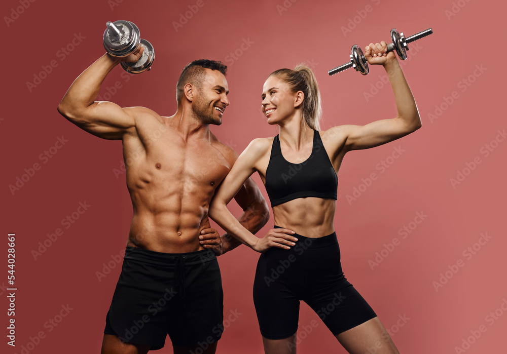 Sport handsome couple with dumbbells at pink background. Fitness male ...
