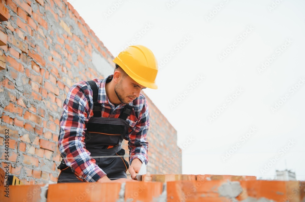 Installing brick wall. Construction worker in uniform and safety ...