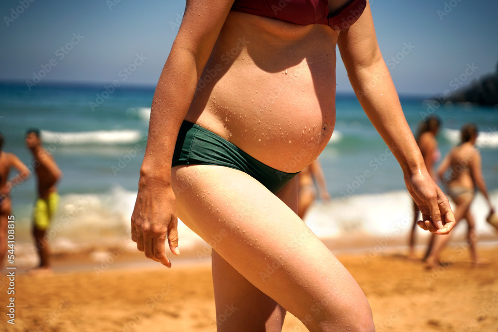 Pregnant woman with a big belly walking on the beach after a swim in the ocean Stock Photo ...