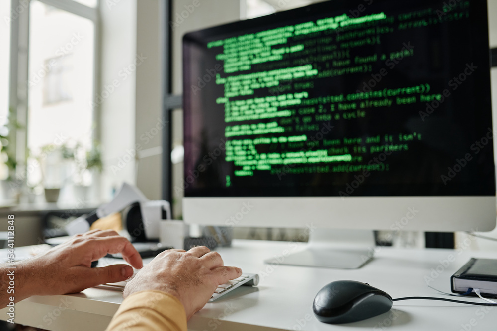 Focus on hands of mature programmer typing on keyboard while sitting in ...