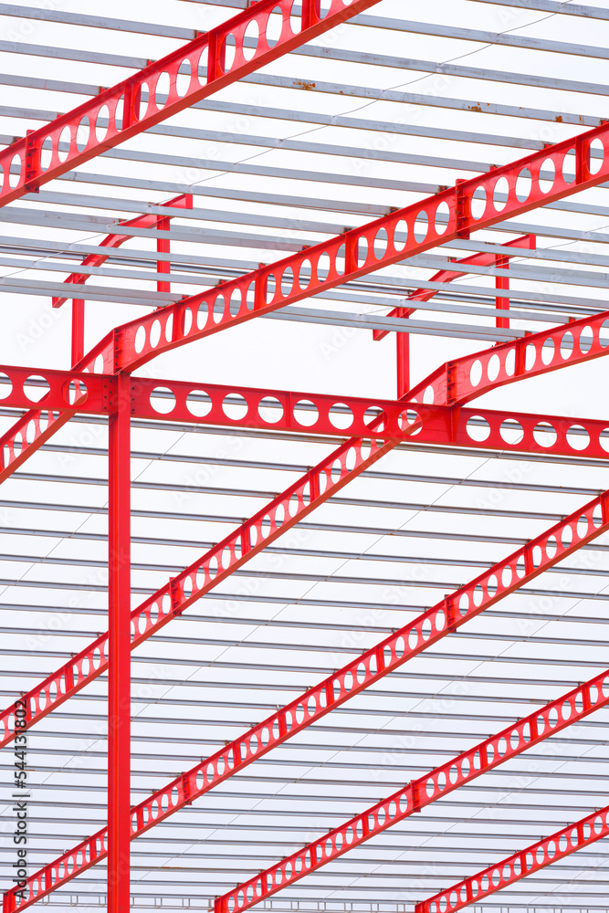 Red castellated beam metal roof structure of large industrial building ...