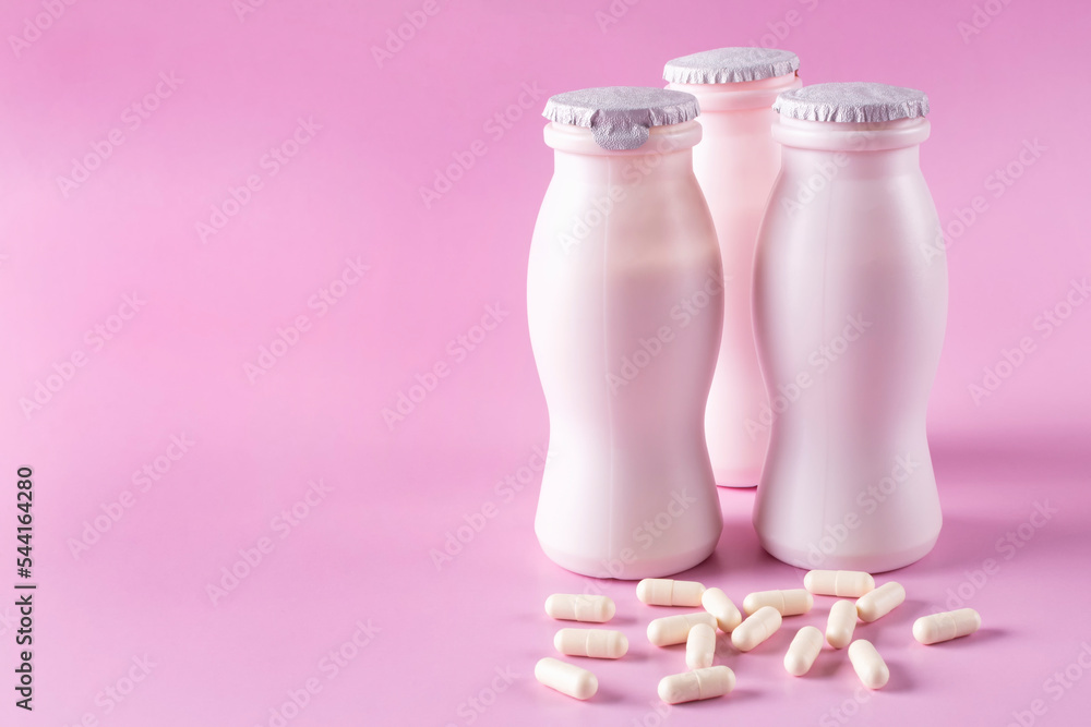 Three bottles of milk yogurt (kefir) and capsules with probiotic on a ...