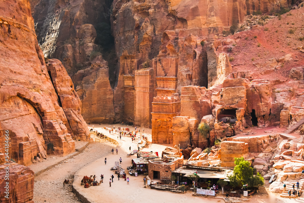 Tourist walk by caves of tombs in ancient city of Petra, Jordan. It is ...