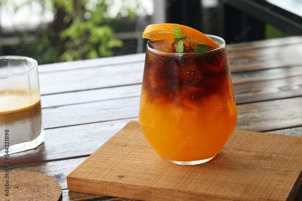 Coffee and Orange juice topping with mint leaves and sliced orange on ...