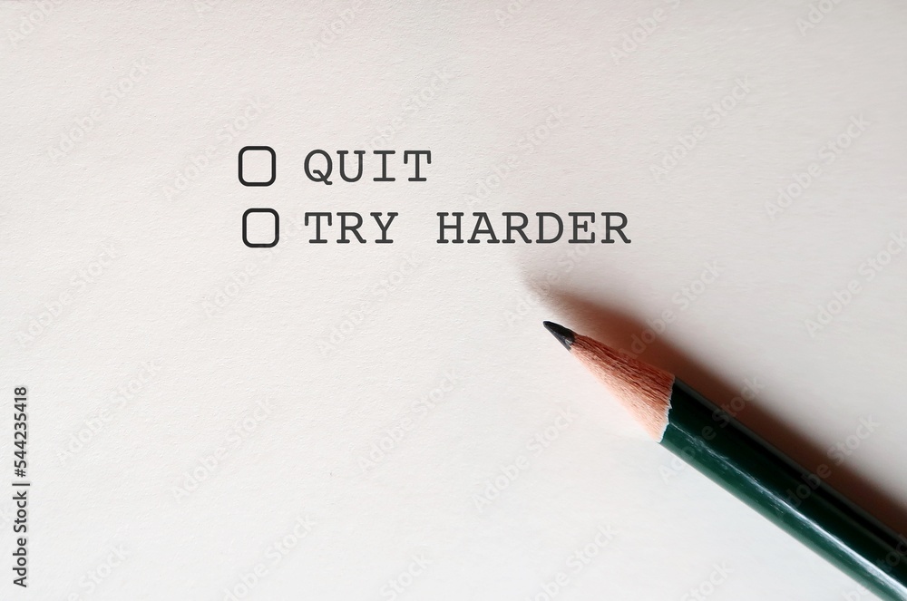 Pen on note paper with tick box QUIT and TRY HARDER, concept of making ...