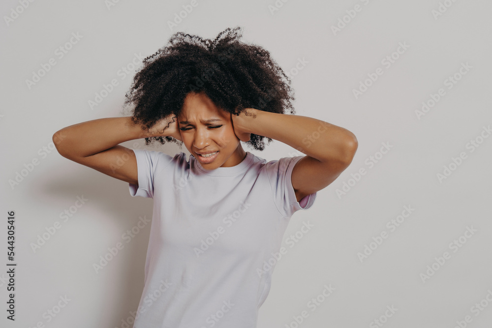 Young angry annoyed african woman covering her ears with both hands to ...