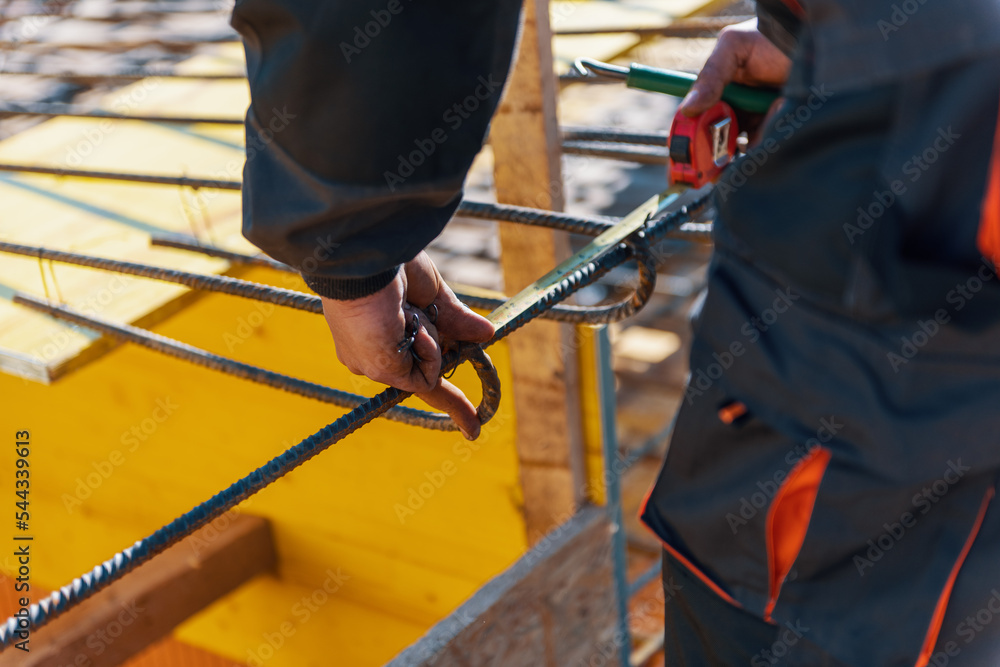 Construction worker tightening the iron mesh rods to steel plates ...